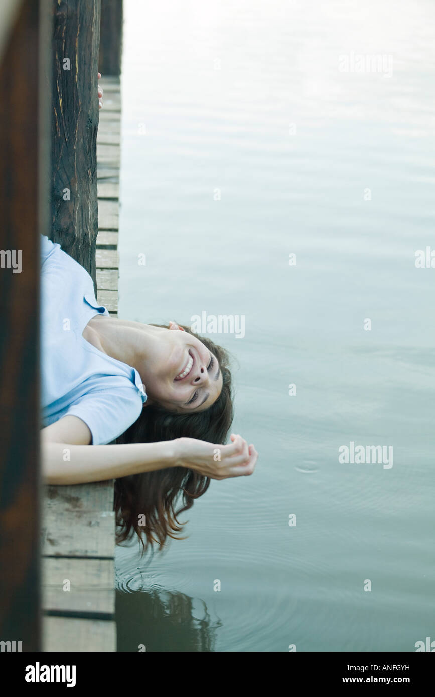 Woman lying on dock with head hanging off edge, smiling Stock Photo - Alamy