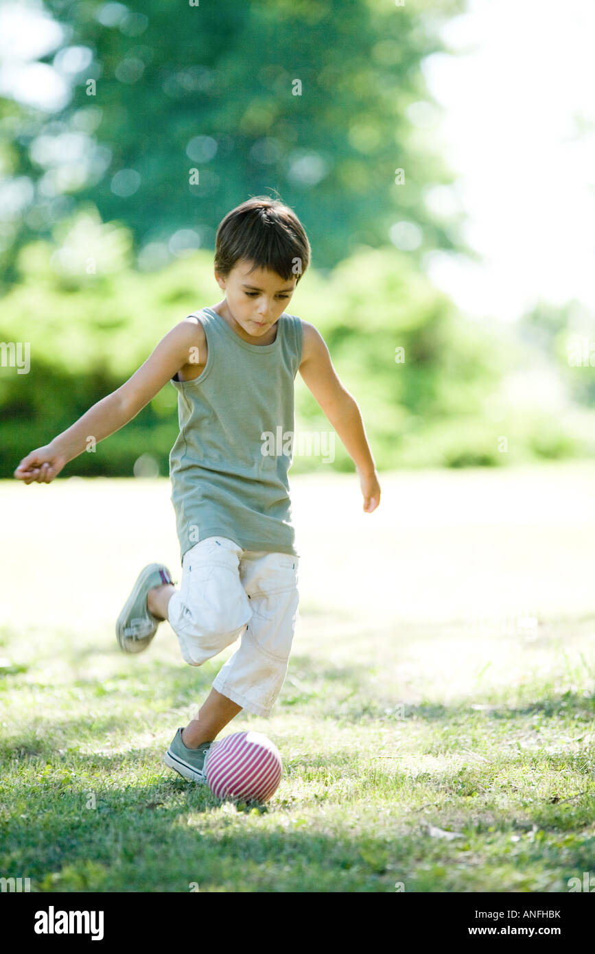 Little boy outdoors, kicking ball Stock Photo - Alamy