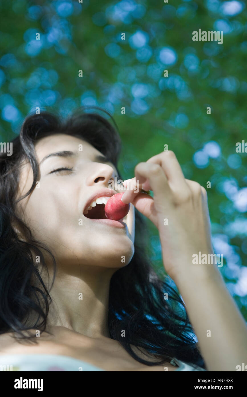 Young woman biting into radish, low angle view Stock Photo - Alamy