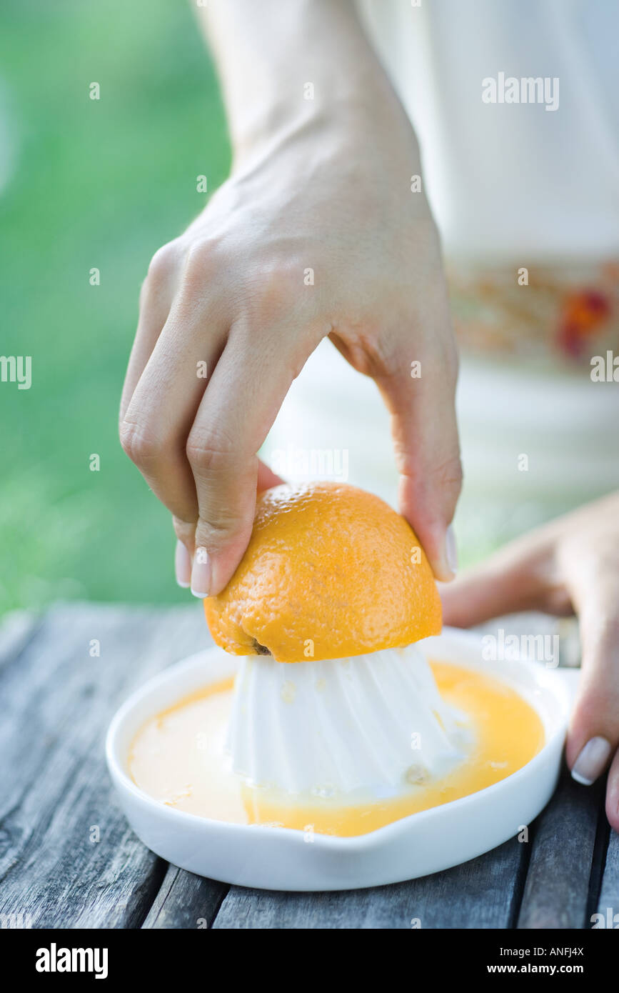 Woman pressing orange with citrus press, close-up, cropped view of ...