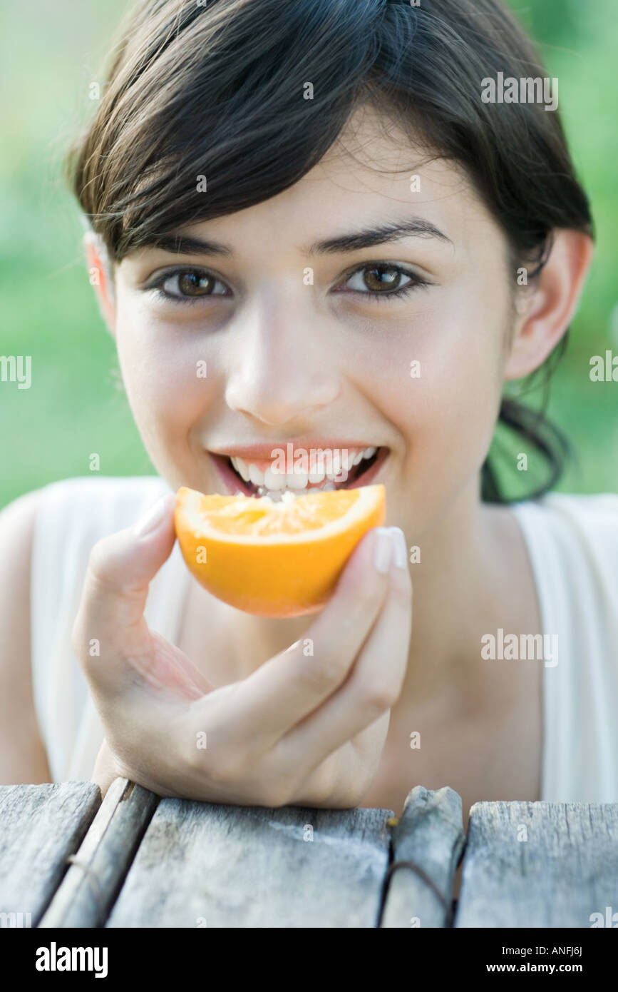 Young woman eating slice of orange Stock Photo - Alamy