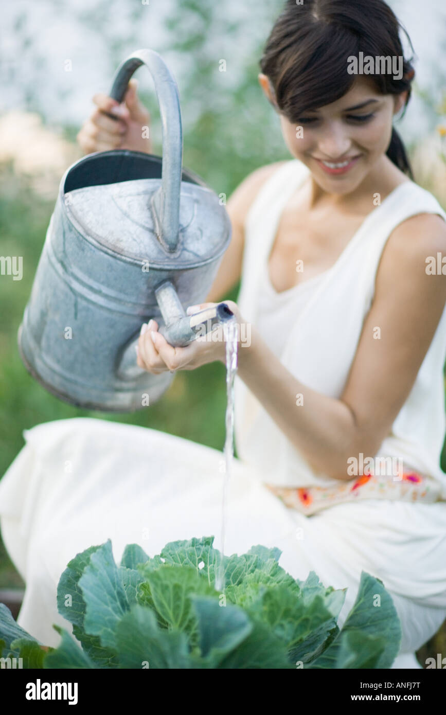 Young woman watering cabbage with watering can Stock Photo - Alamy