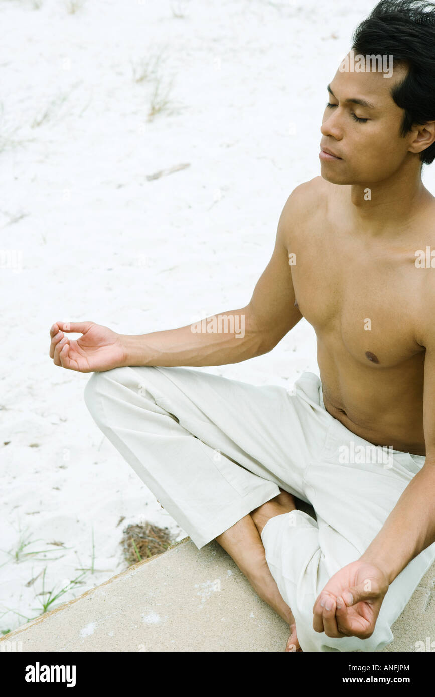 Barechested man sitting in lotus position, eyes closed, cropped Stock ...