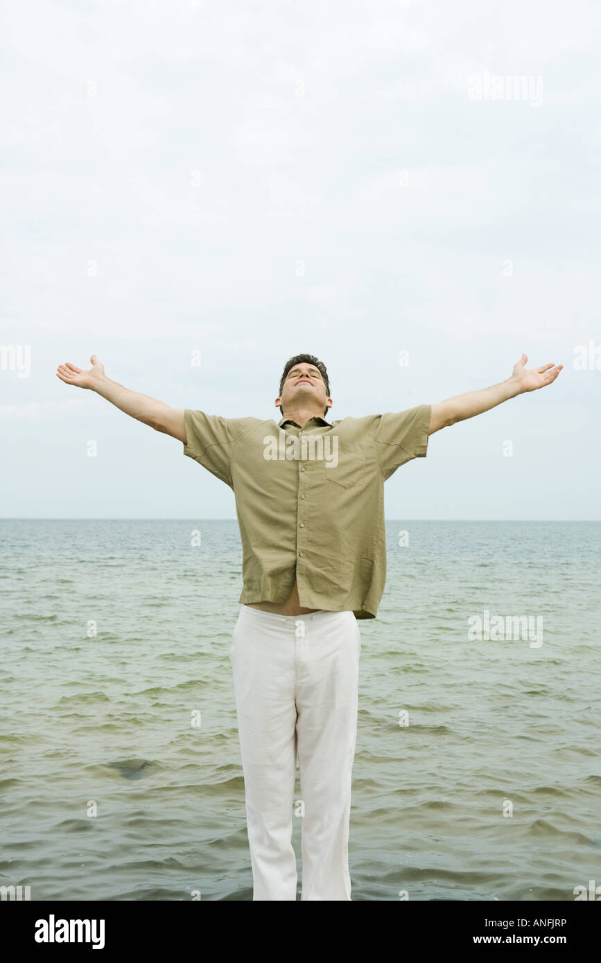 Man standing with head back and arms out, in front of ocean Stock Photo ...