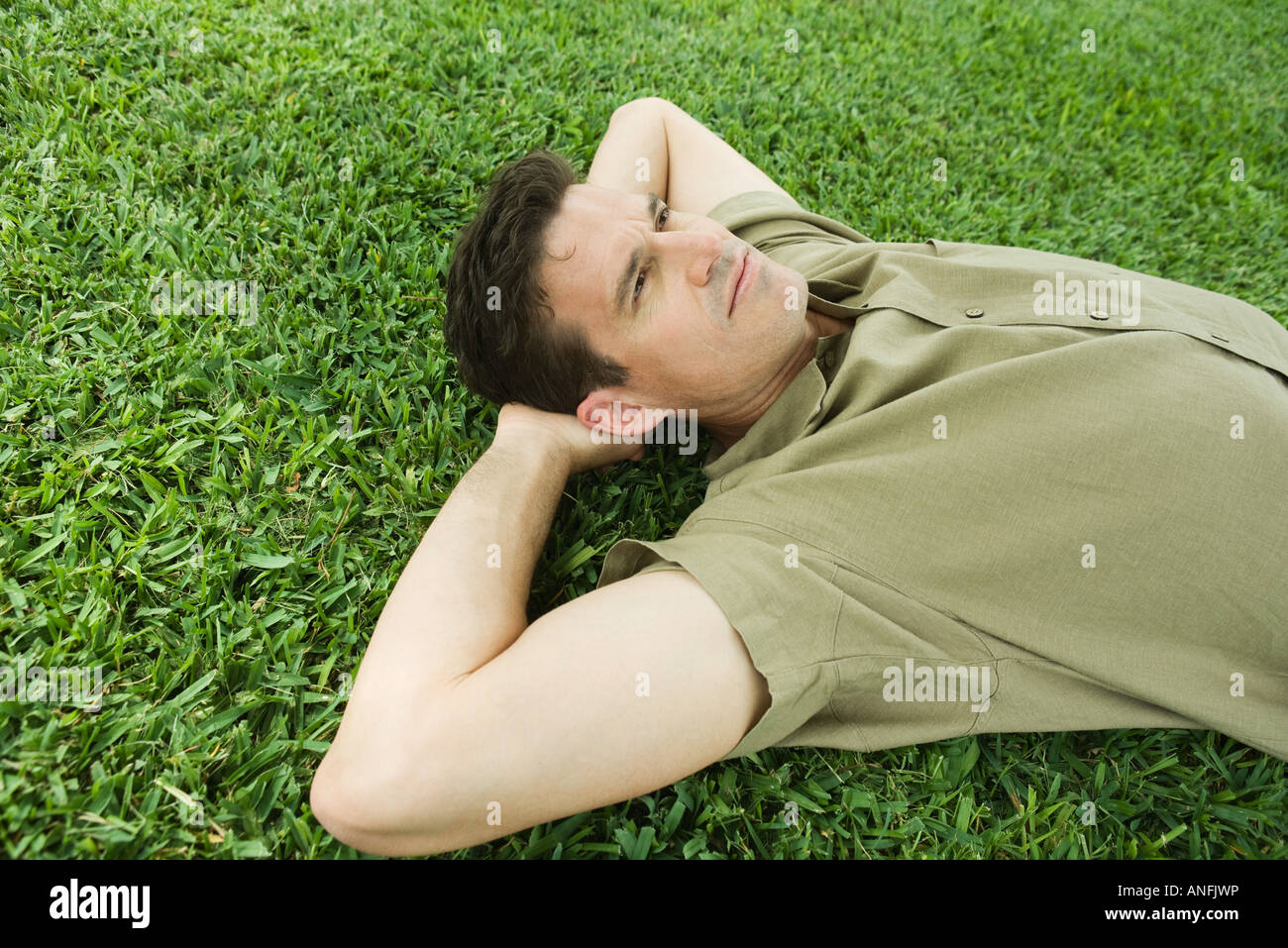 Man lying on grass, hands behind head Stock Photo - Alamy