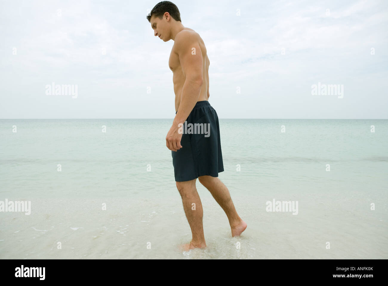Man standing in surf, full length Stock Photo - Alamy
