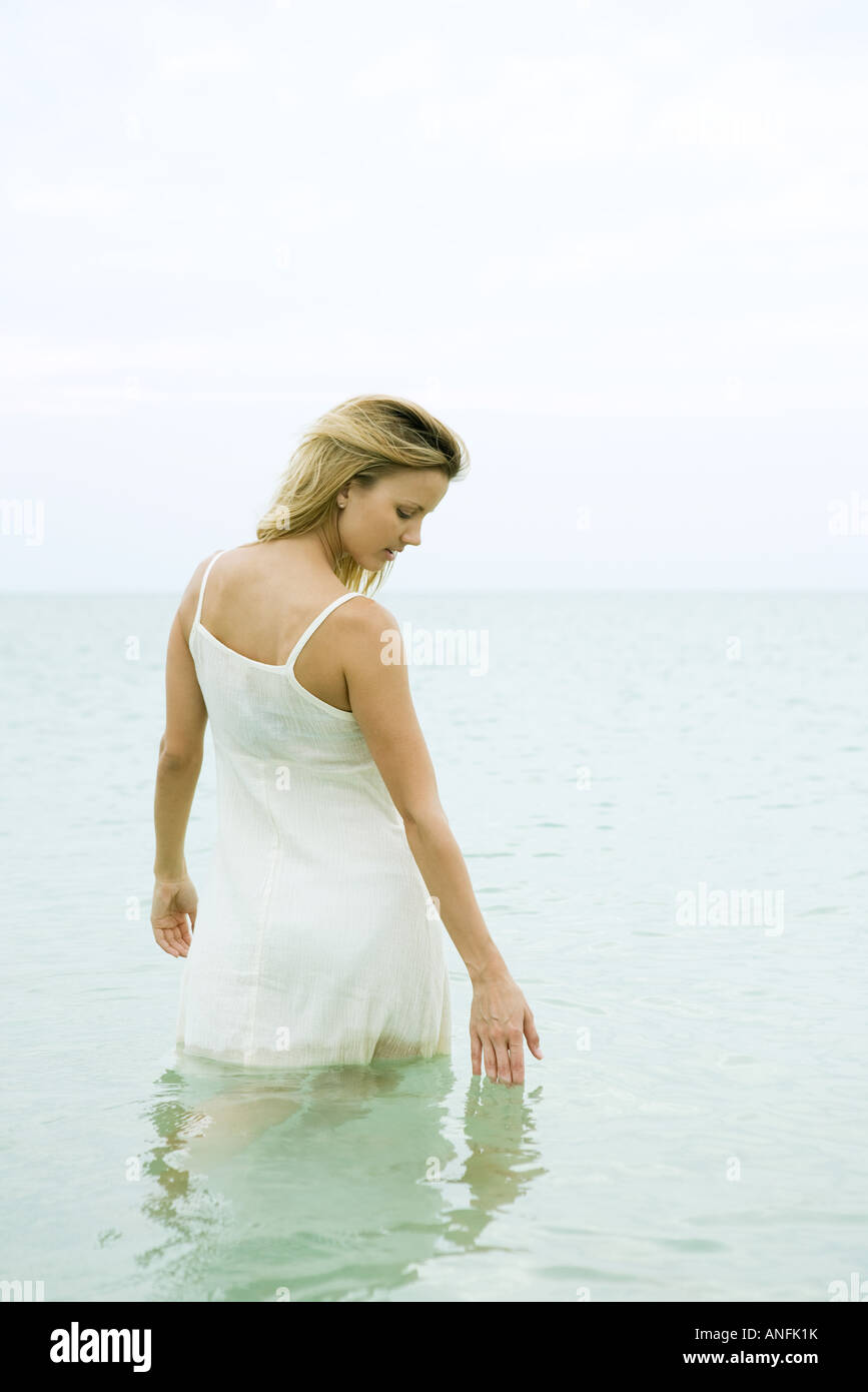 Woman standing knee deep in ocean, touching surface of water Stock ...