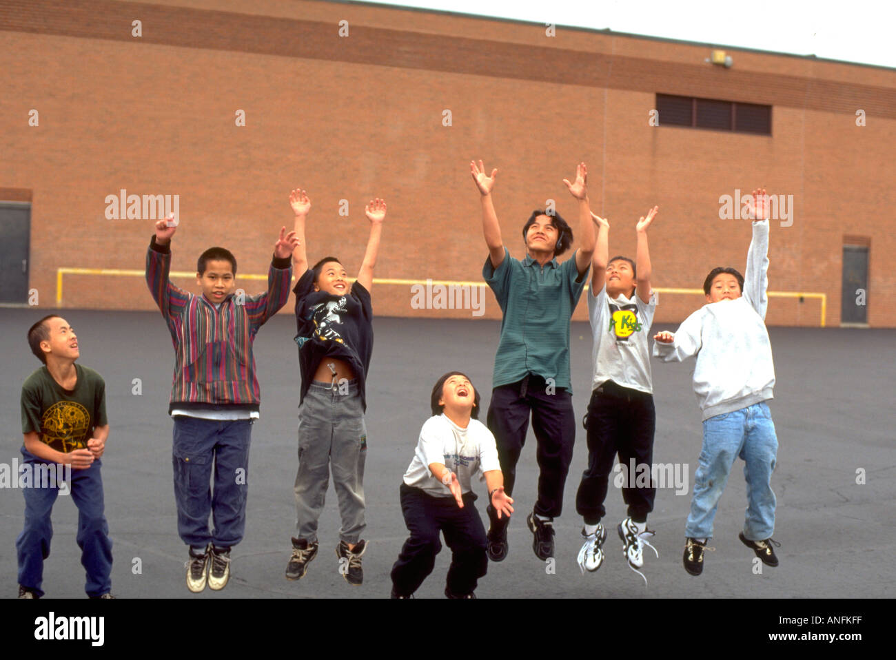 Asian American students age 11 jumping at recess during summer school ...