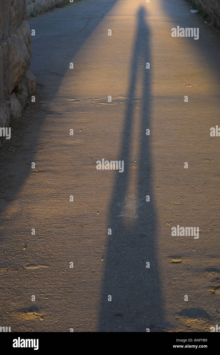 long human sun shadow casted on narrow road with heavy shadows on the ...