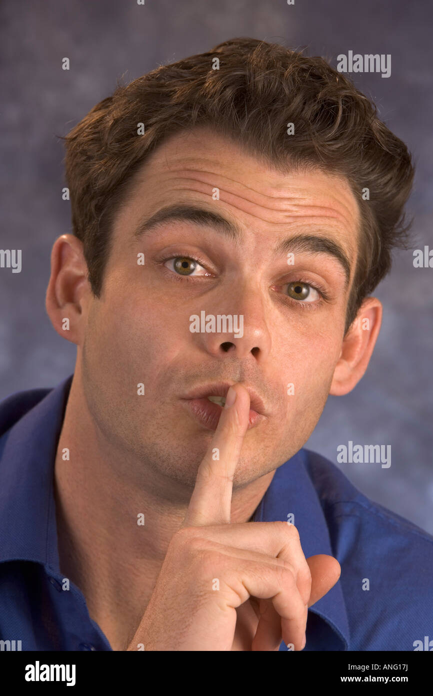 Man with his finger to his lips saying shush or quiet Stock Photo - Alamy