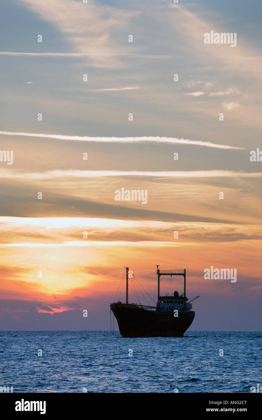 Beached, grounded silhouetted shipwrecked vessel; Cargo ship Honduran ...