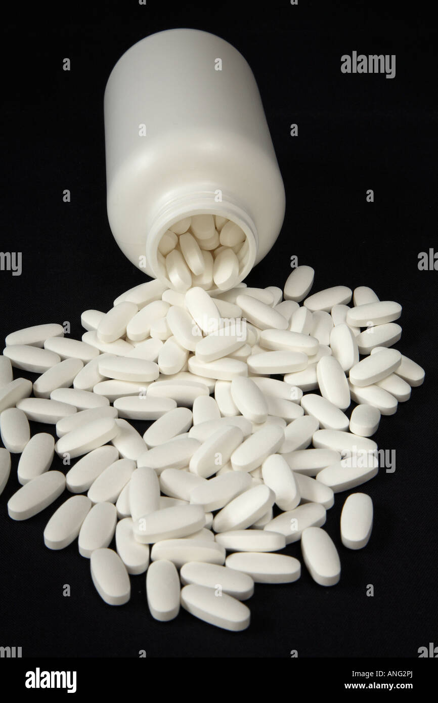 Plain white bottle on it's side with large pool of white oval tablets ...