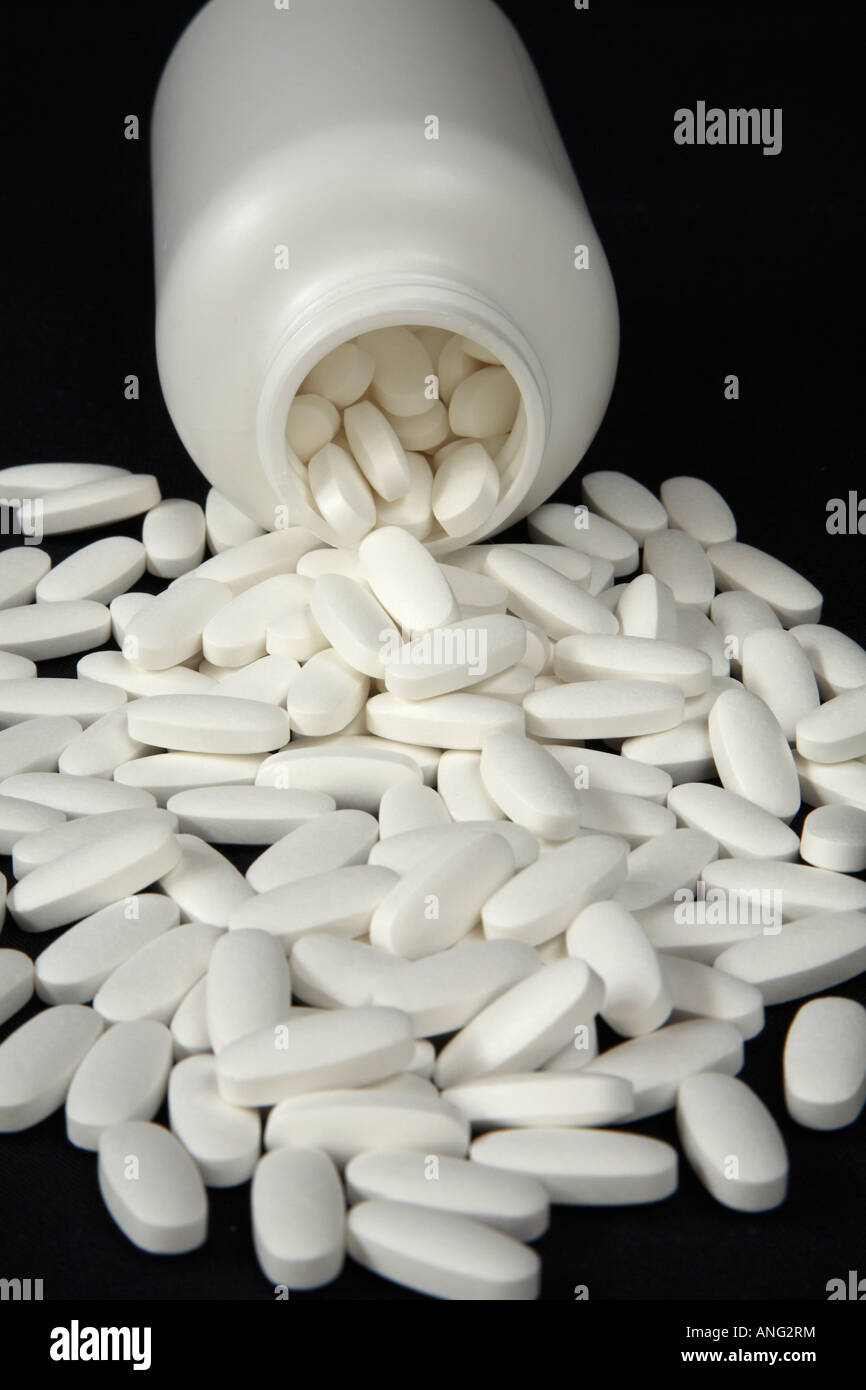 Plain white bottle on it's side with large pool of white oval tablets ...