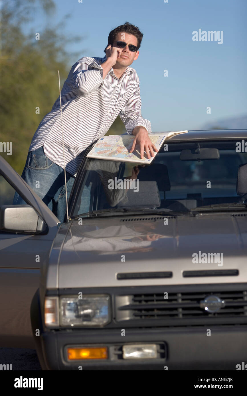 A man lost while driving checks a road map while on a cell phone Stock ...