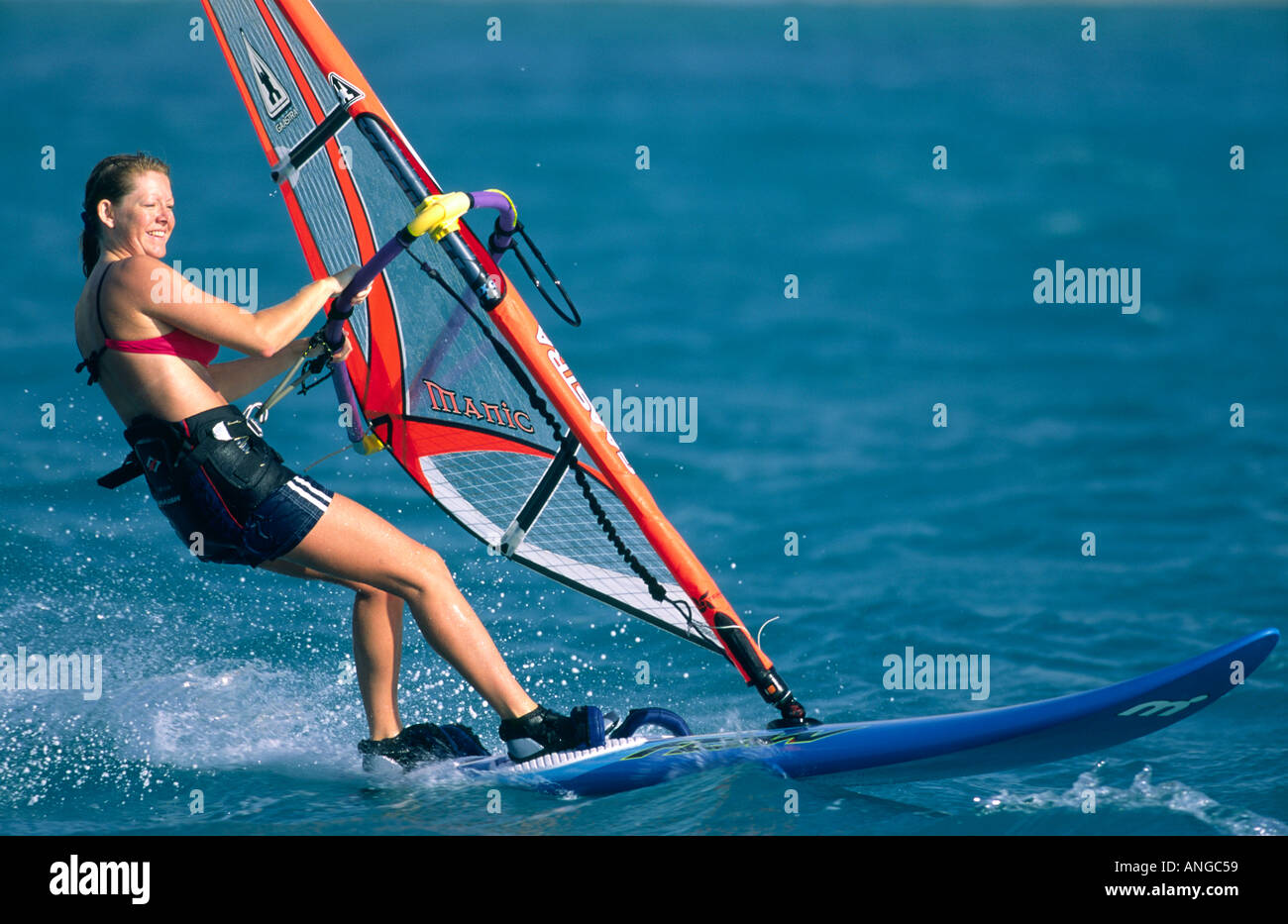 side view of single female windsurfer on blue water of Red Sea Sinai ...