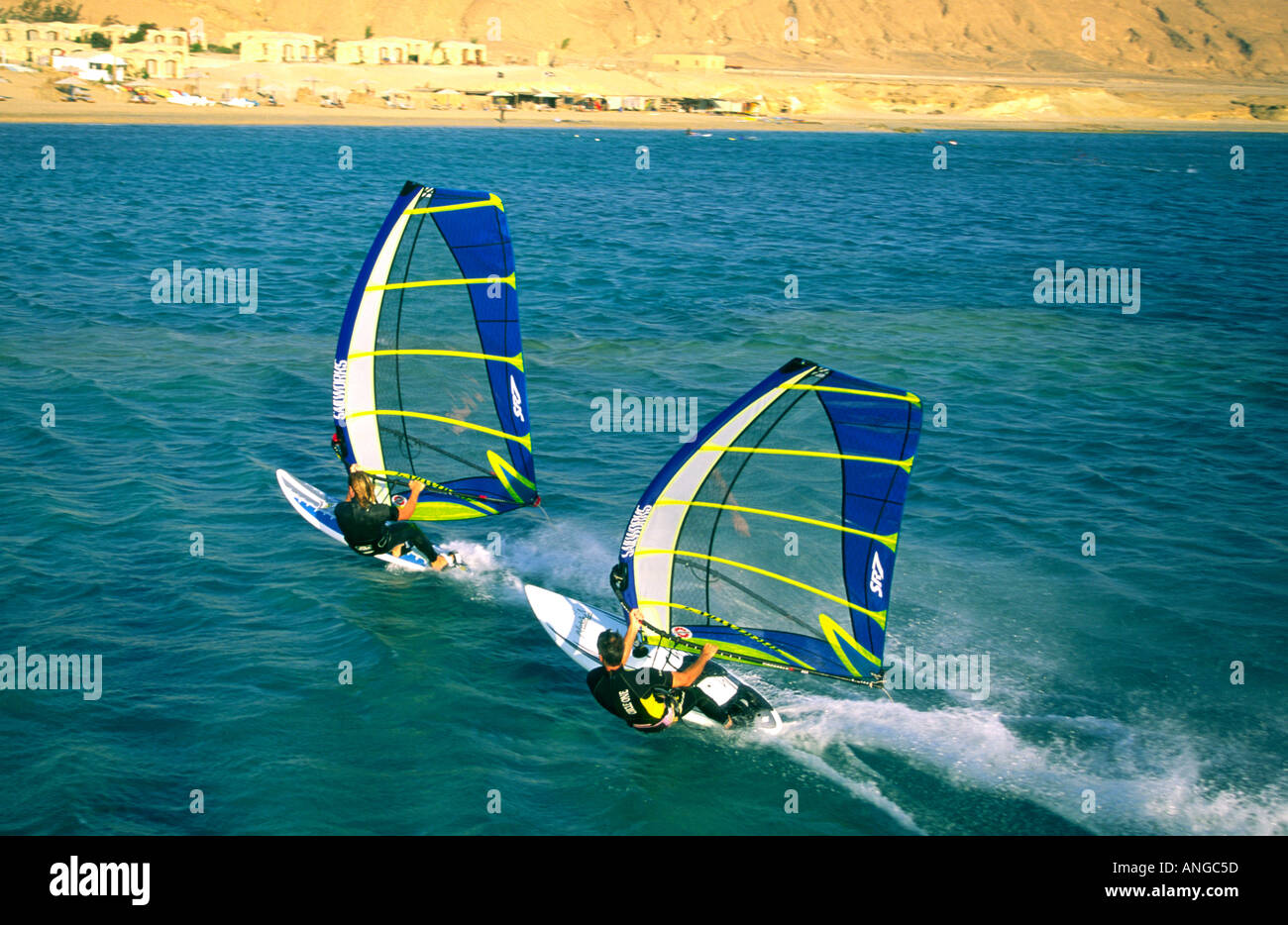 2 windsurfers from above sailing in line formation on blue water of Red ...