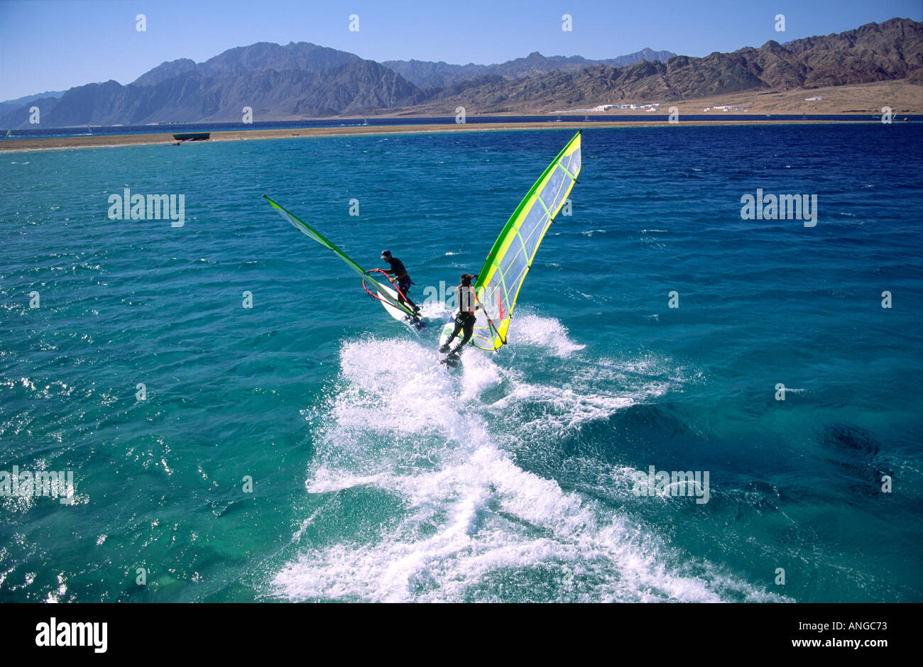 View from above of 2 windsurfers nearly colliding in shallow clear ...