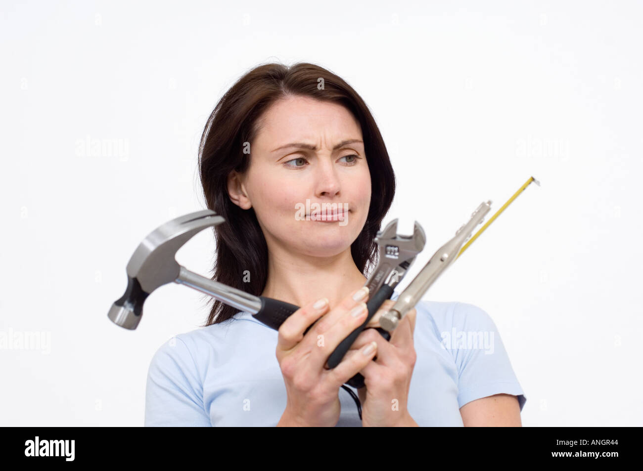 woman with her hands full of tools looking confused Stock Photo - Alamy