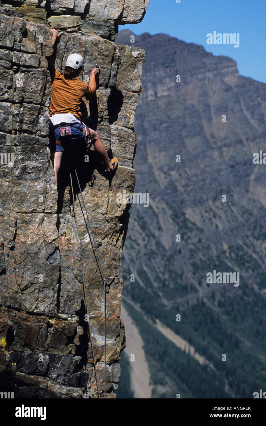 A young man clipping in on Cardiac Arete on Grand Sentinel, Alberta ...