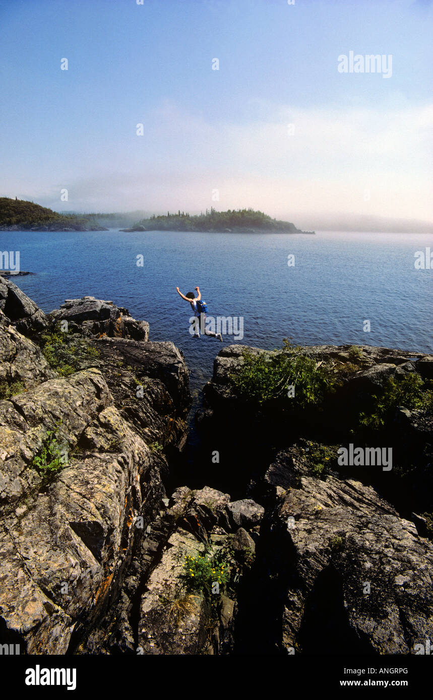 Man jumping rocks along the shoreline of Newfoundland, Canada Stock ...