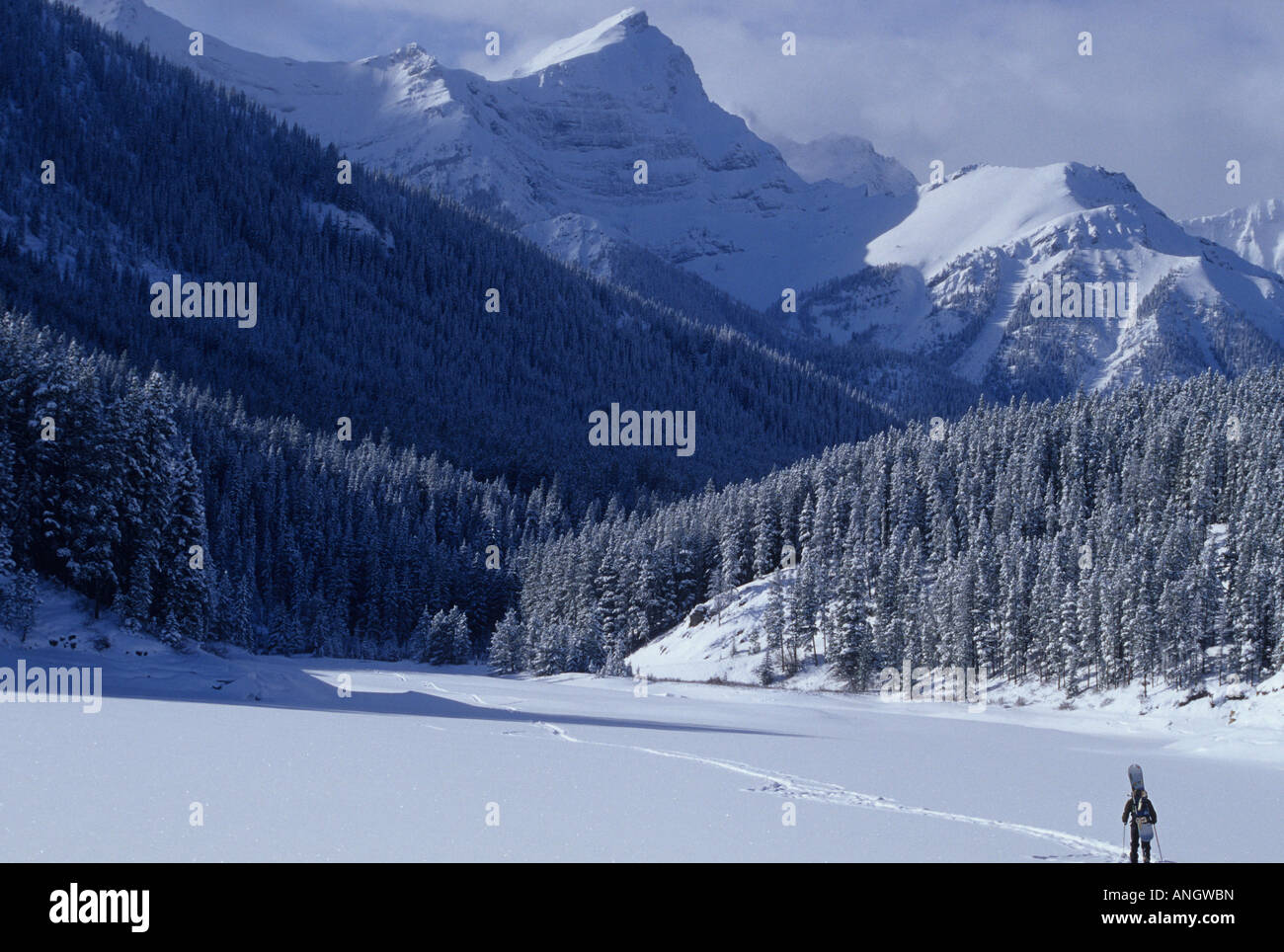 A snowboarder trekking across a lake to get to a nice back country ...