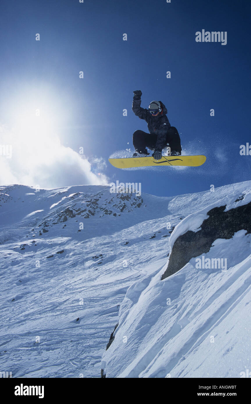 A snowboarder grabbing his board after jumping a cliff at Lake Louise ...