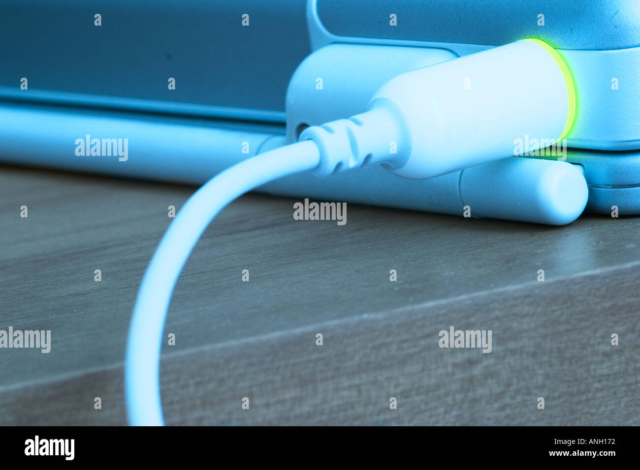 Glowing blue and green wire connected to notebook laptop computer on a ...