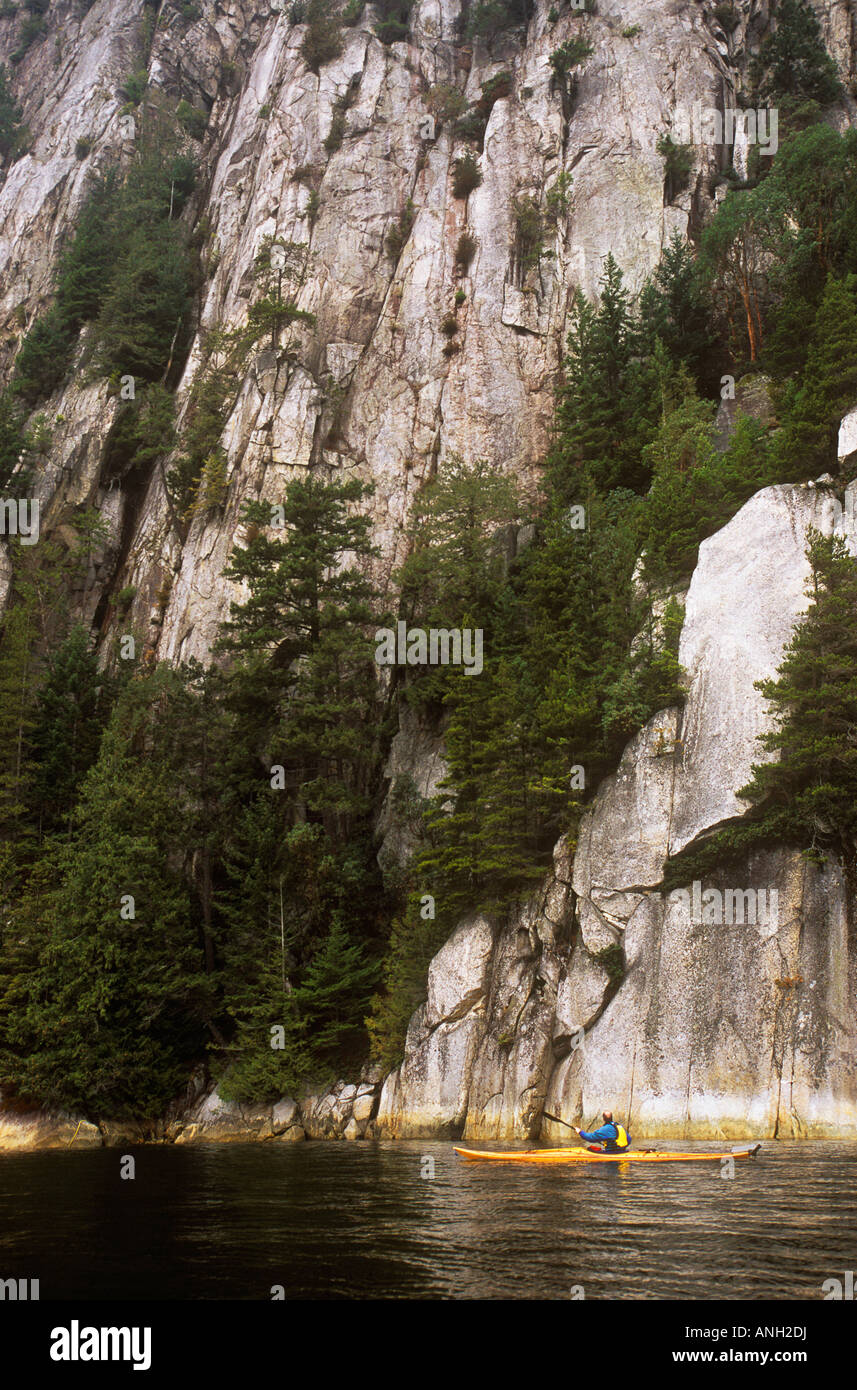 Sea kayaking under seaside cliffs, Howe Sound near Squamish, British ...