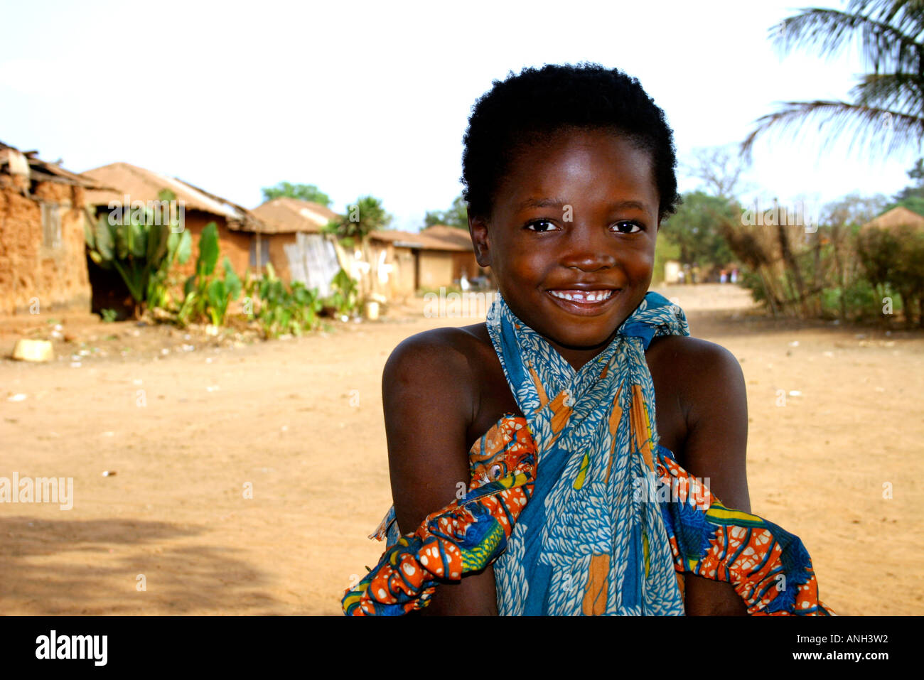 A young African girl (from Togo) wears traditional clothes gives a big ...