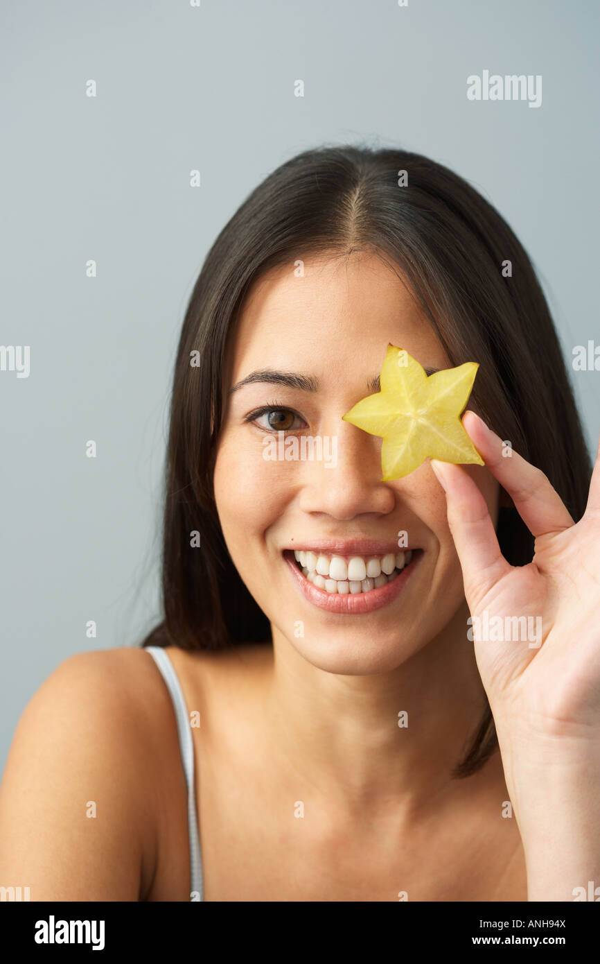 Asian woman holding star fruit over eye Stock Photo - Alamy