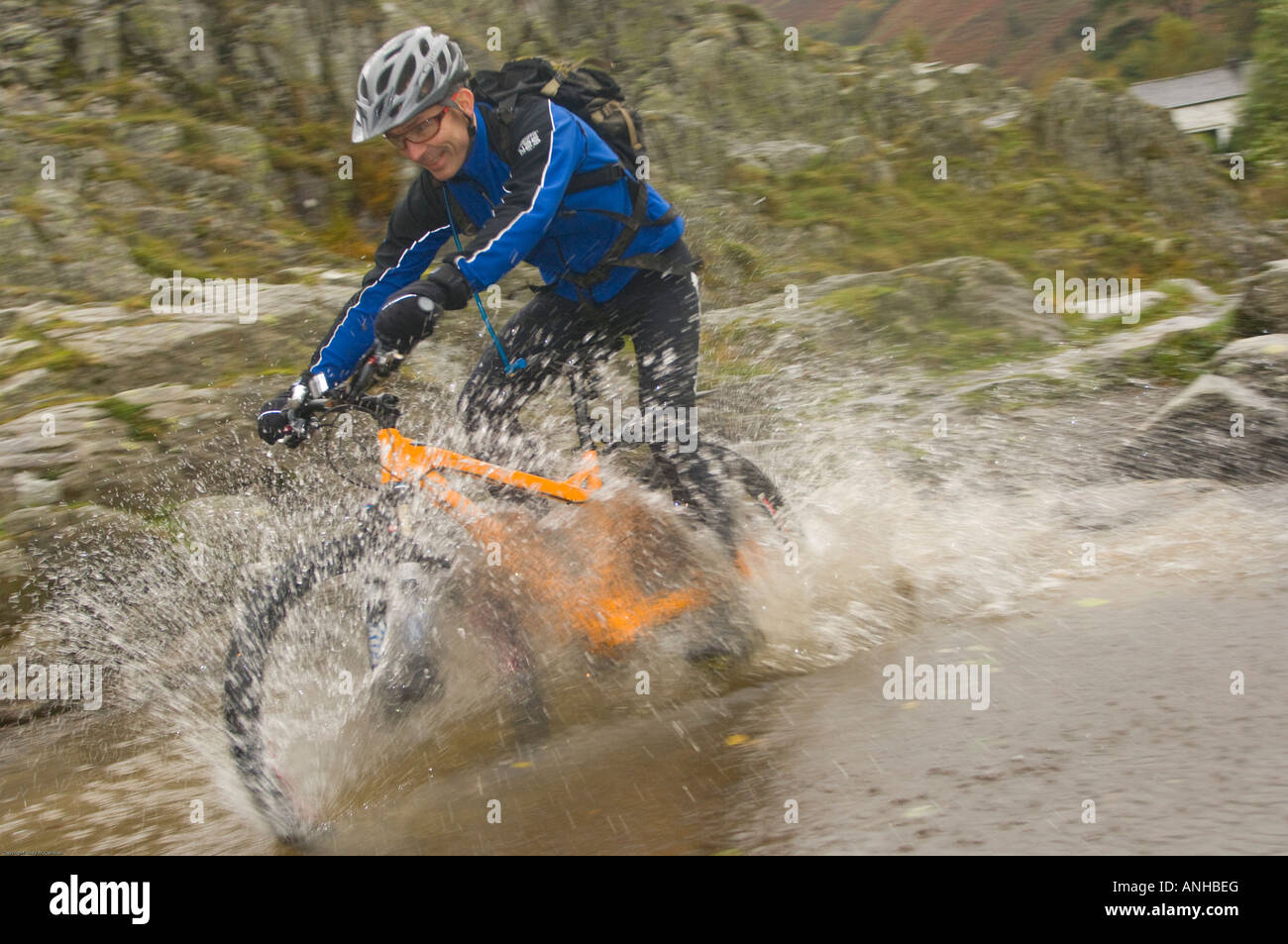 A mountain biker splash through a river on a rainy day in the Lake ...