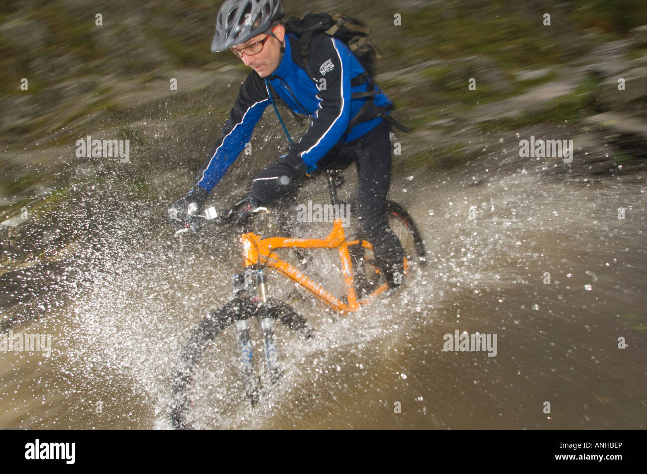 A mountain biker splash through a river on a rainy day in the Lake ...