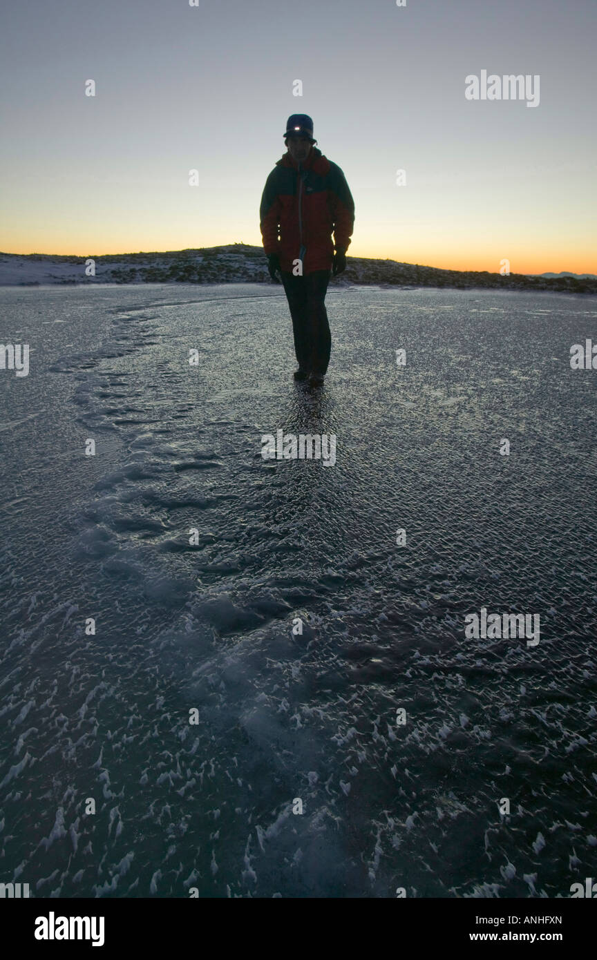 A walker on a frozen tarn on the summit of Red Screes in the Lake ...