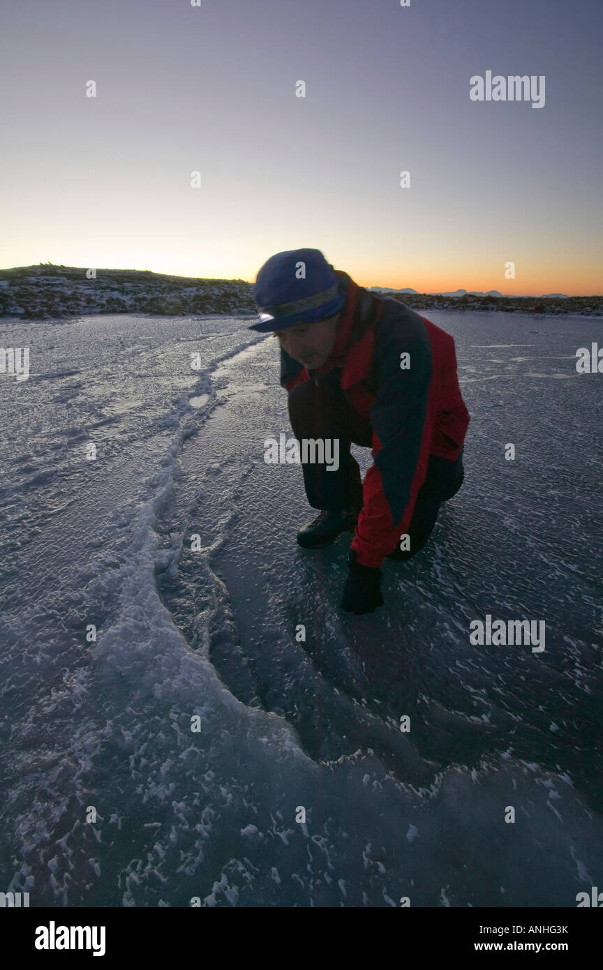 A walker on a frozen tarn on the summit of Red Screes in the Lake ...