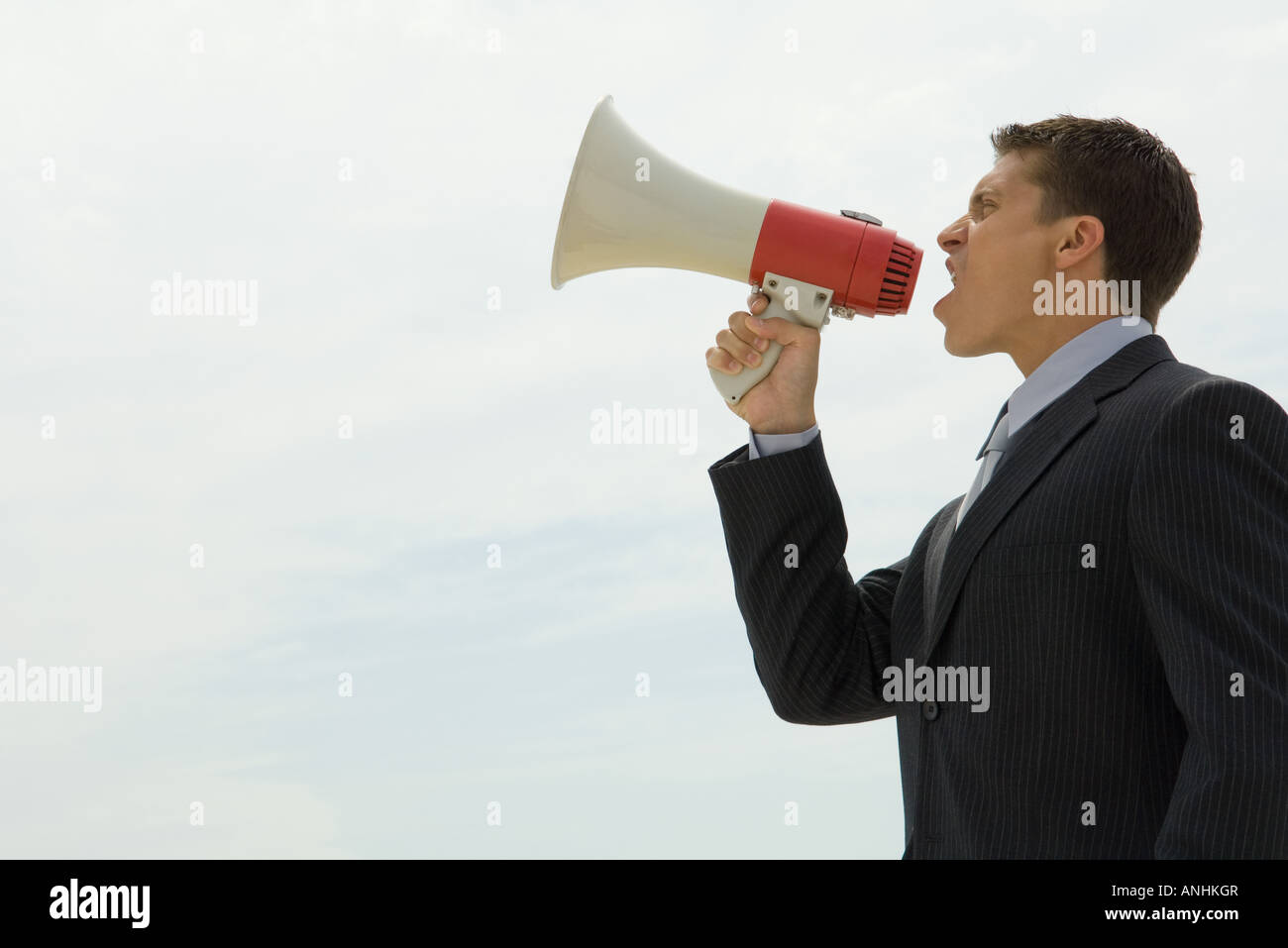 Young businessman shouting into megaphone, side view Stock Photo - Alamy