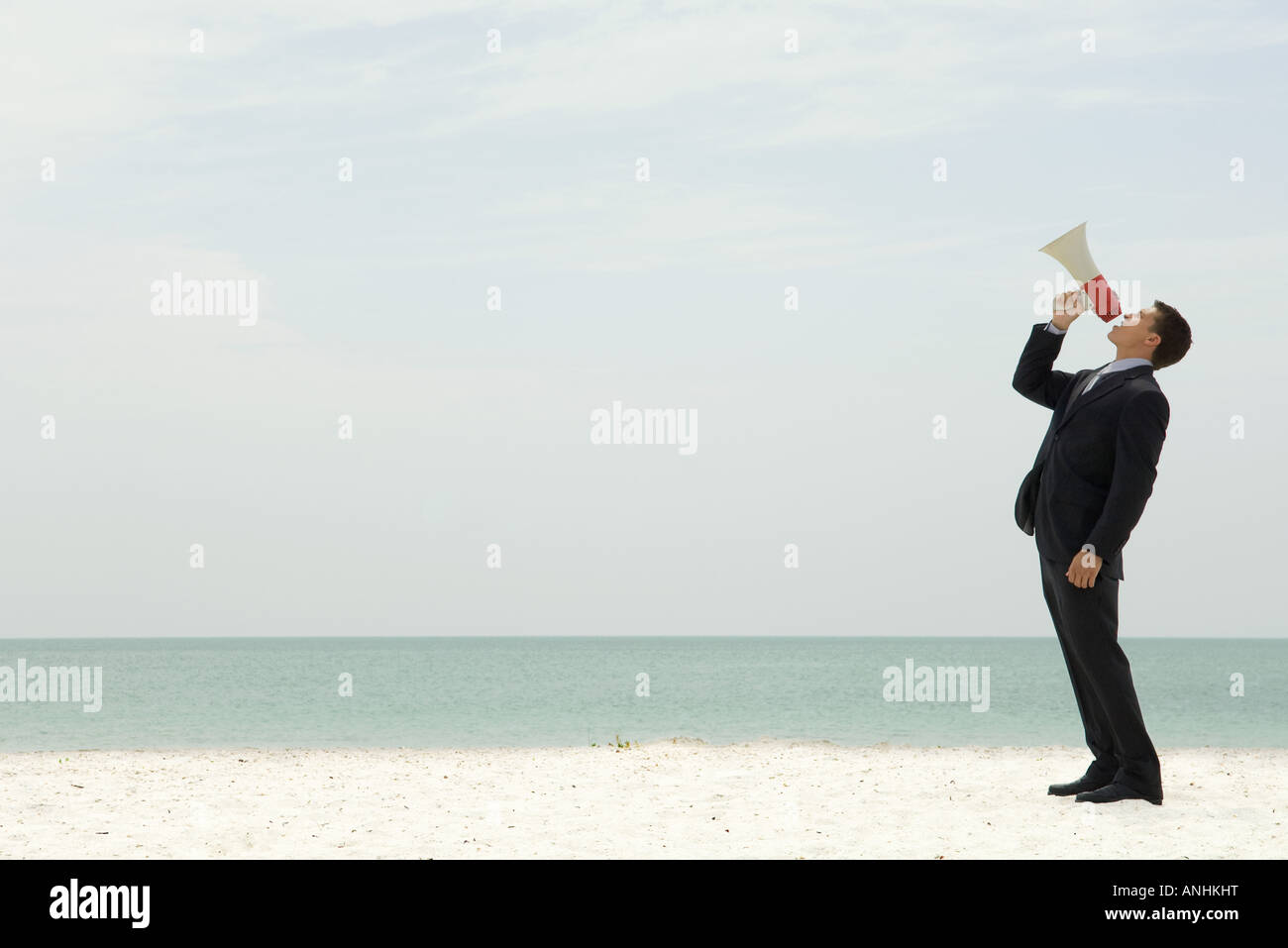 Businessman standing at the beach shouting into megaphone Stock Photo ...