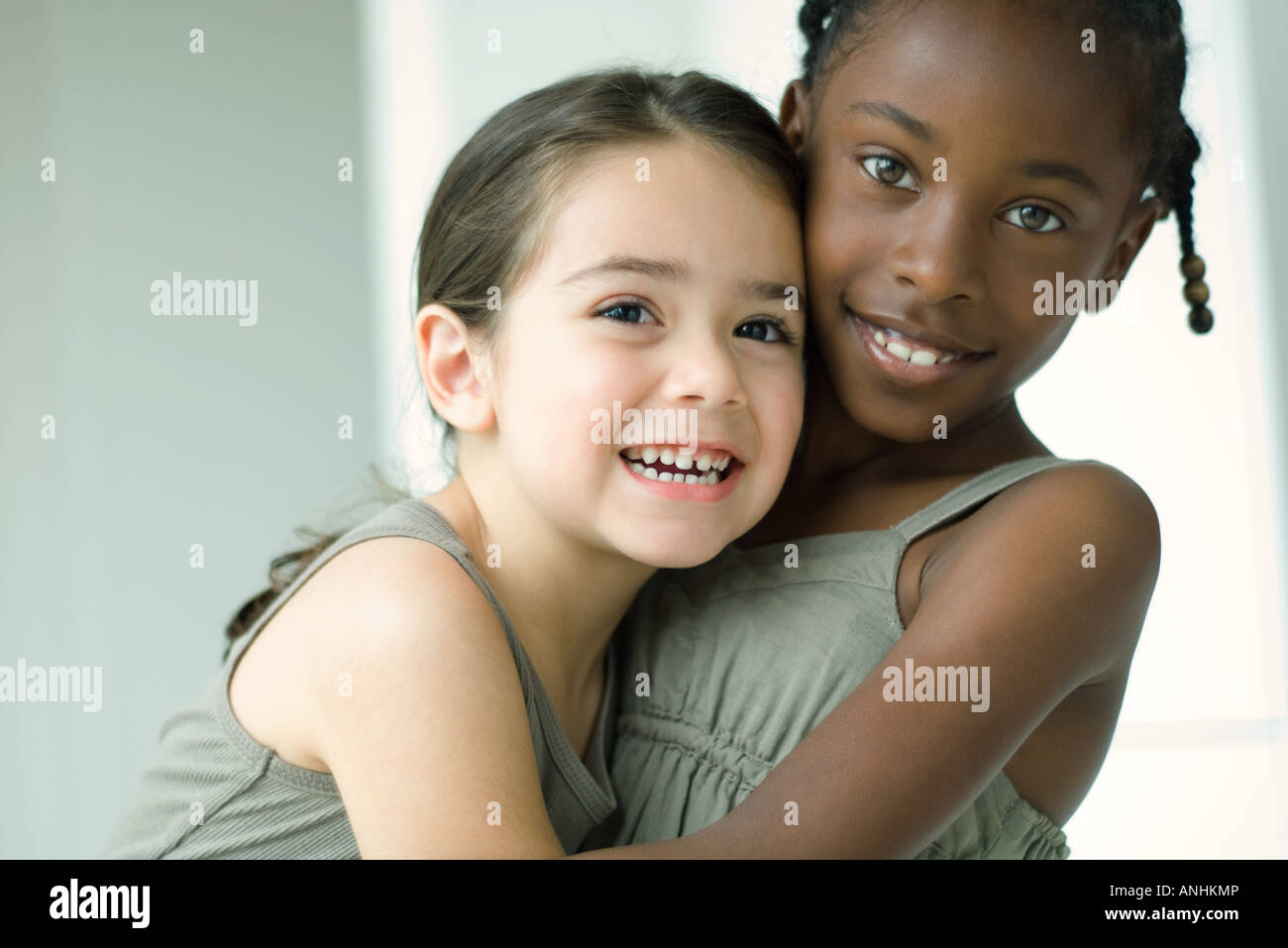 Two young female friends embracing, both smiling at camera Stock Photo ...