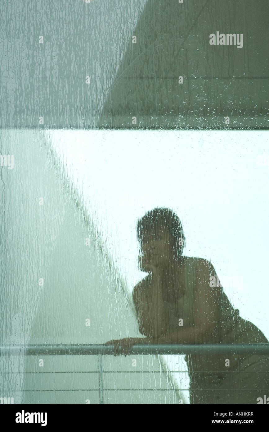 Woman looking through window in rain Stock Photo - Alamy