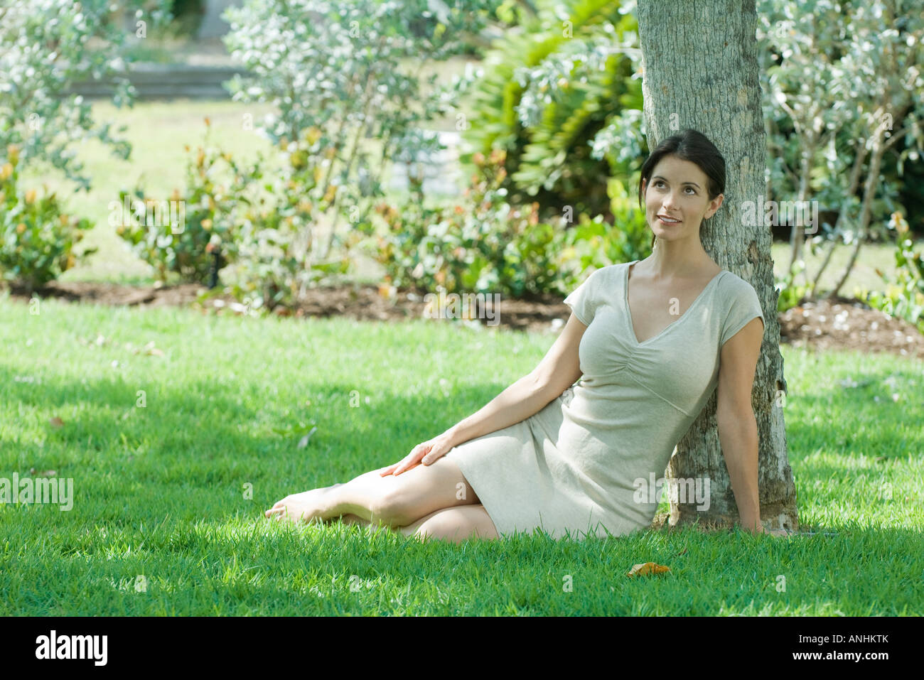 Mid adult woman sitting against tree hi-res stock photography and ...