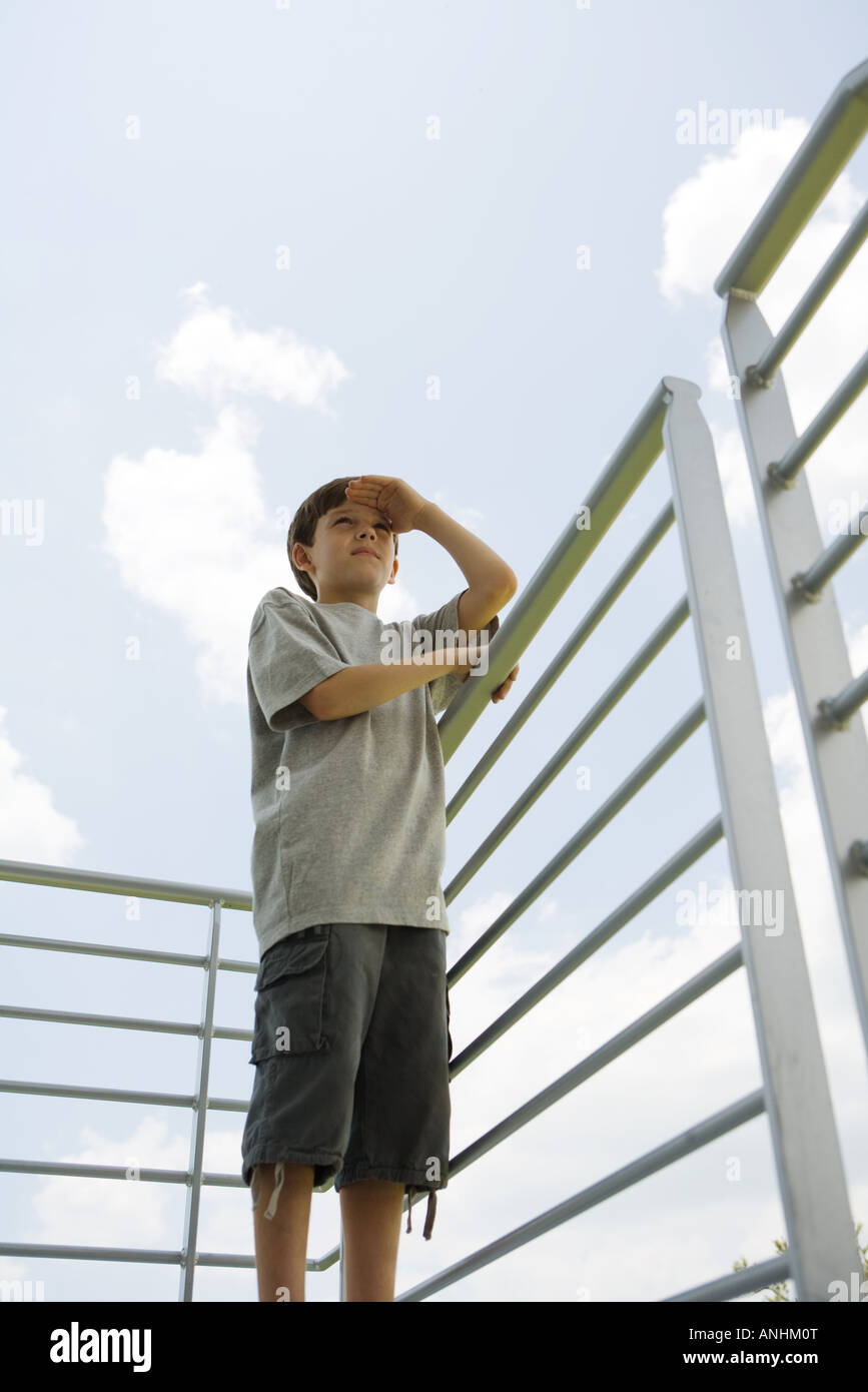 Boy standing on balcony shading eyes, looking at view Stock Photo - Alamy