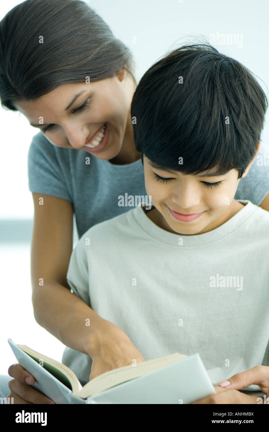 Teenage girl helping boy read book Stock Photo - Alamy