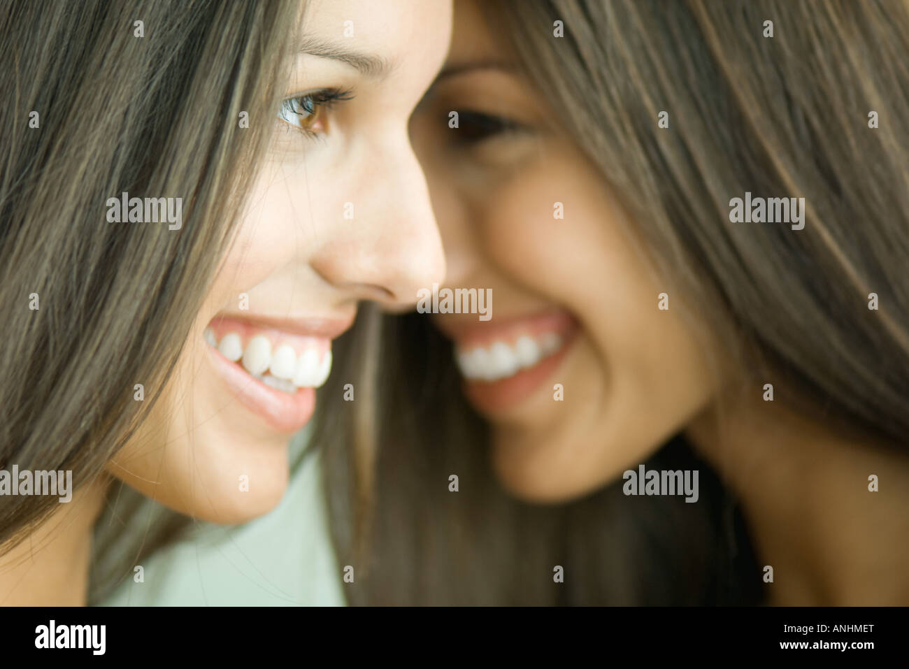Two twin teenage sisters smiling, face to face, profile Stock Photo - Alamy