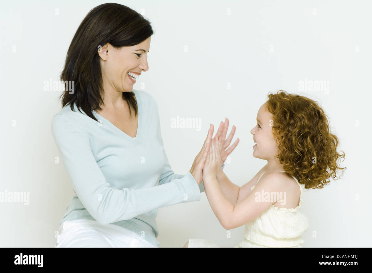 Woman and little girl playing clapping game, side view Stock Photo - Alamy