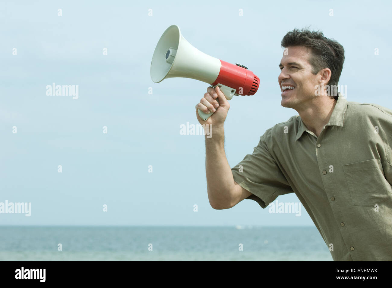 Man using megaphone, ocean horizon in background Stock Photo - Alamy