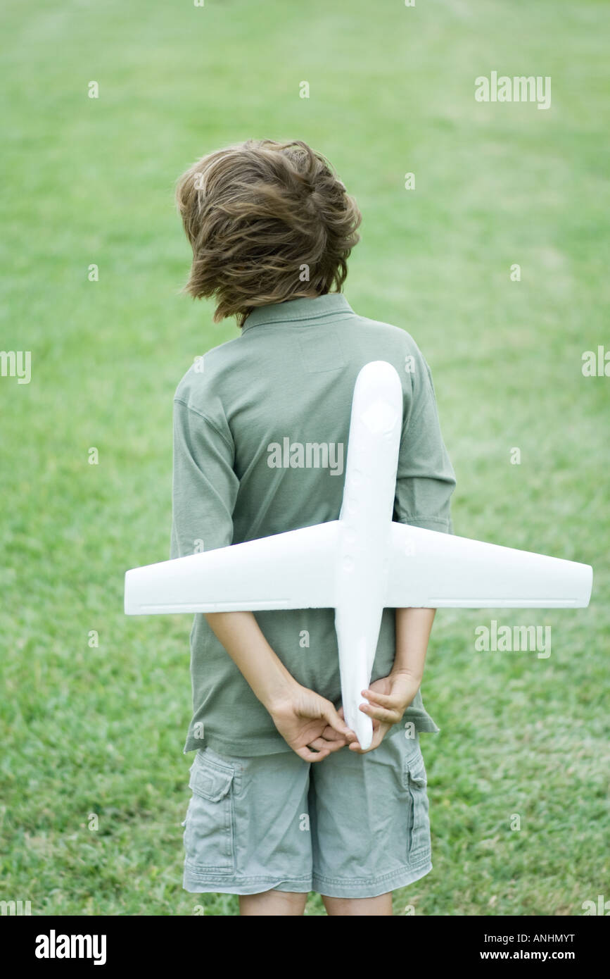 Boy holding toy airplane behind back, rear view Stock Photo - Alamy