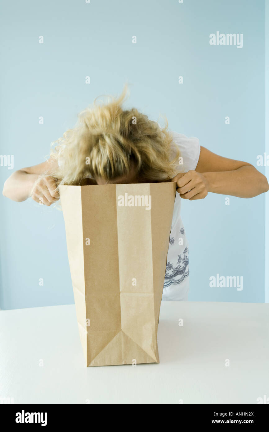 Woman leaning forward, looking into grocery bag Stock Photo - Alamy