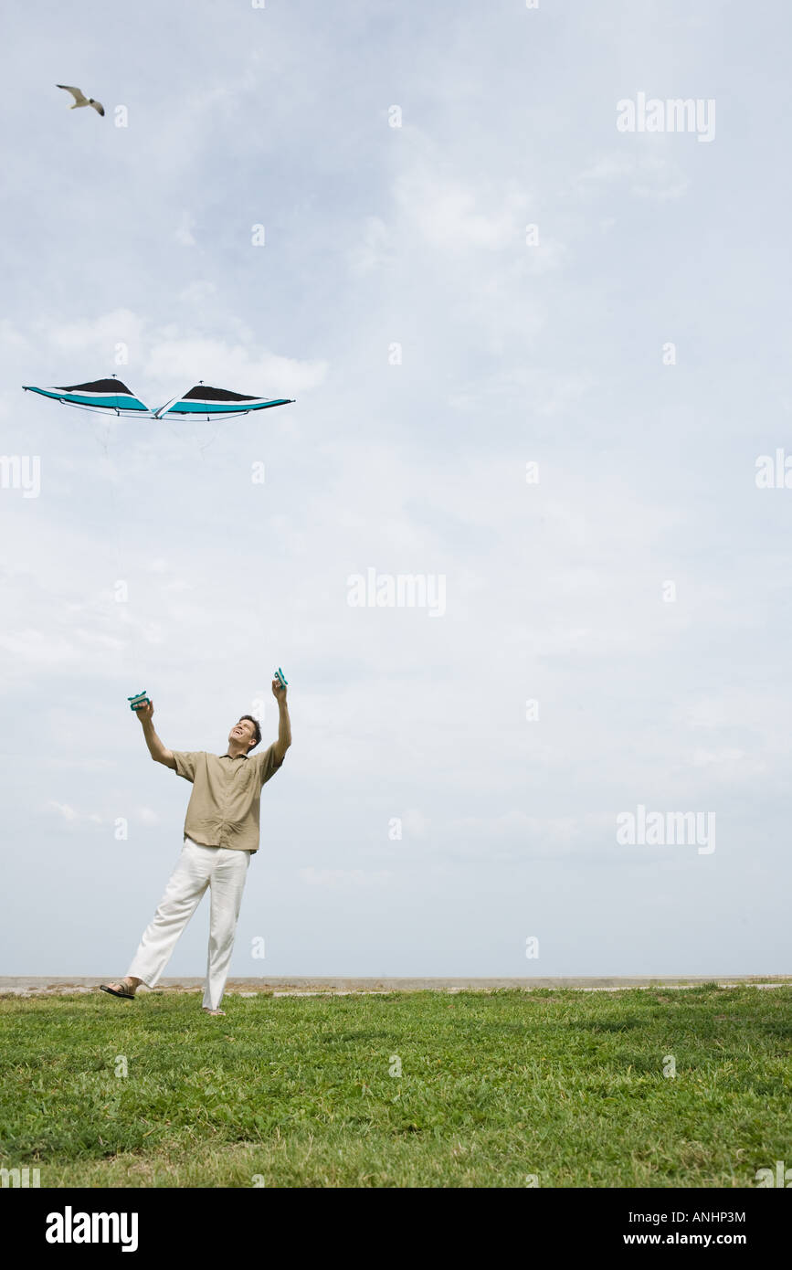 Man flying kite, arms raised, full length Stock Photo - Alamy