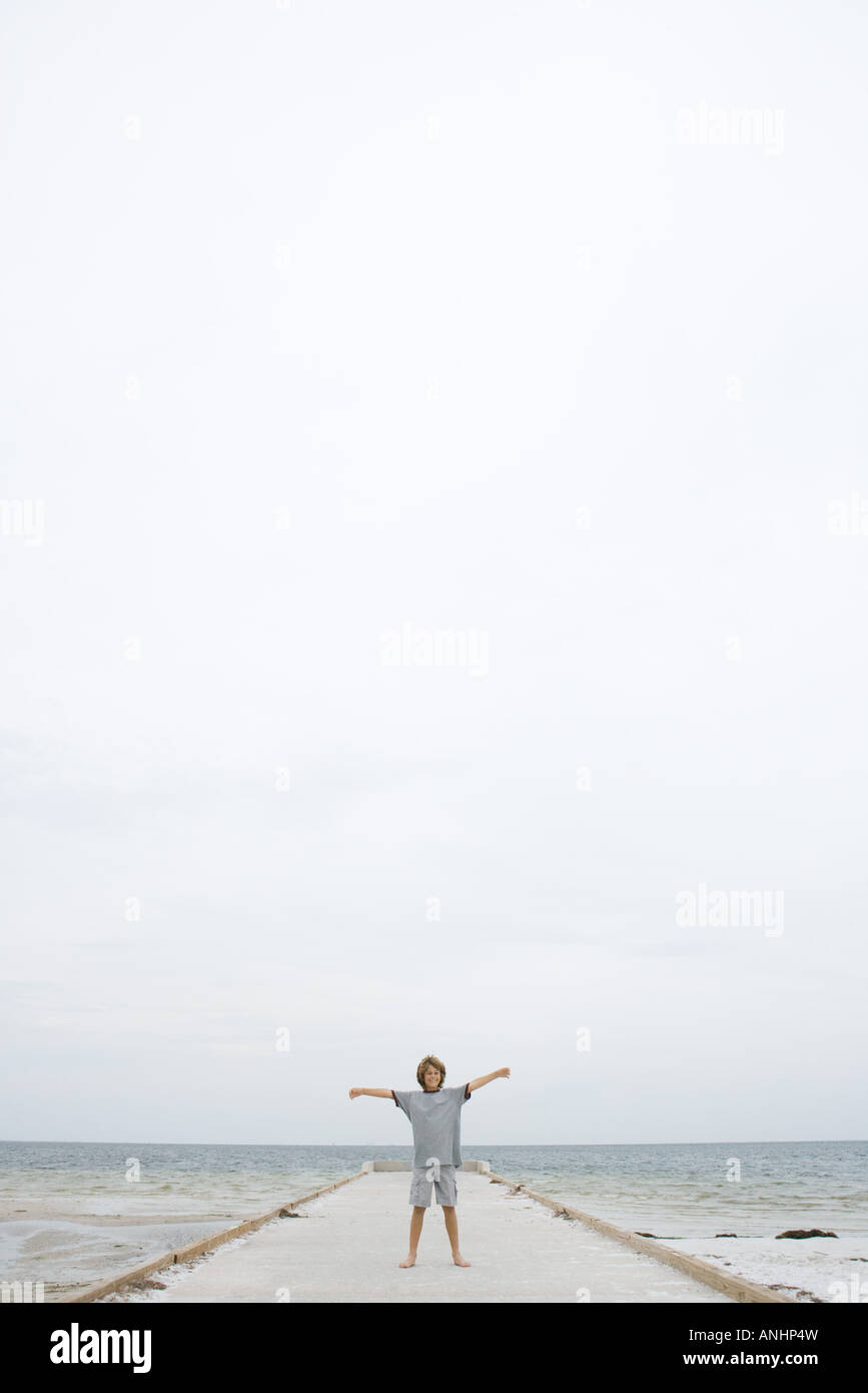 Boy standing on pier at mid-distance, arms out Stock Photo - Alamy