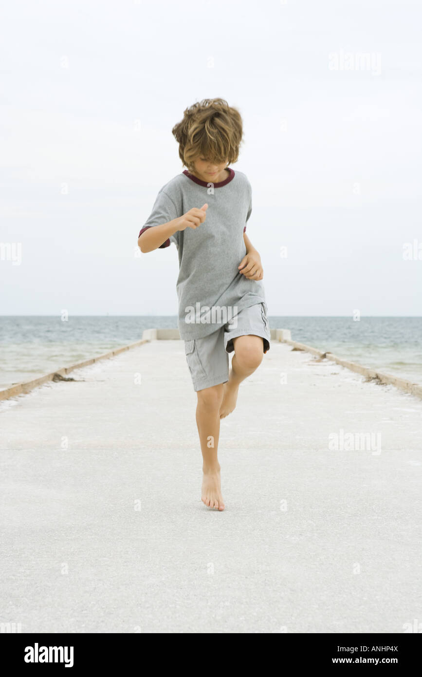 Boy running on pier, looking down, front view Stock Photo - Alamy