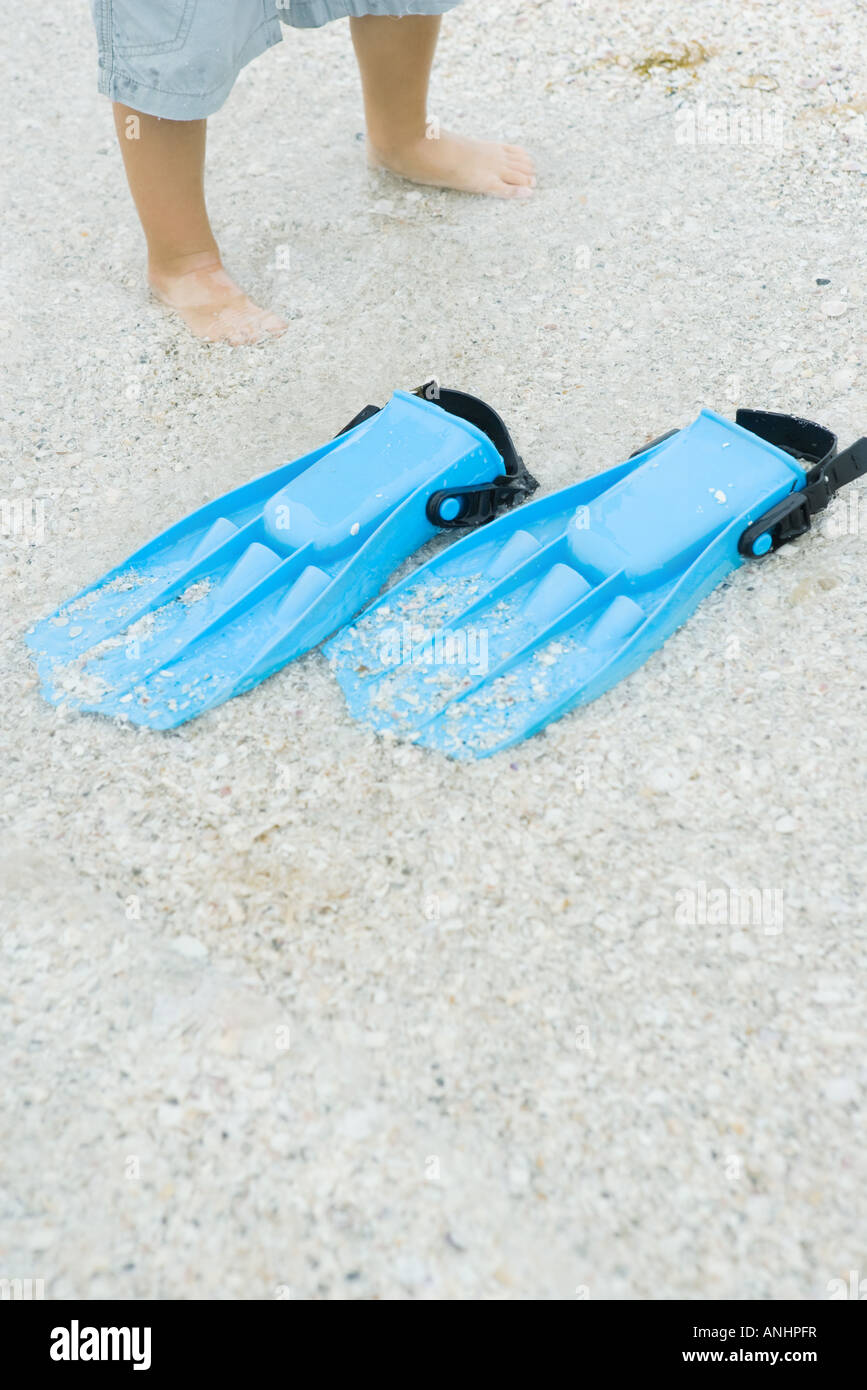 Child standing next to flippers on sand, cropped view Stock Photo - Alamy